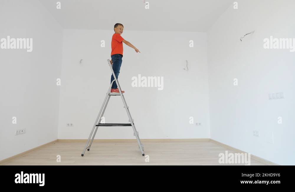 Child up on renovation ladder jump on father arms, children play Stock ...