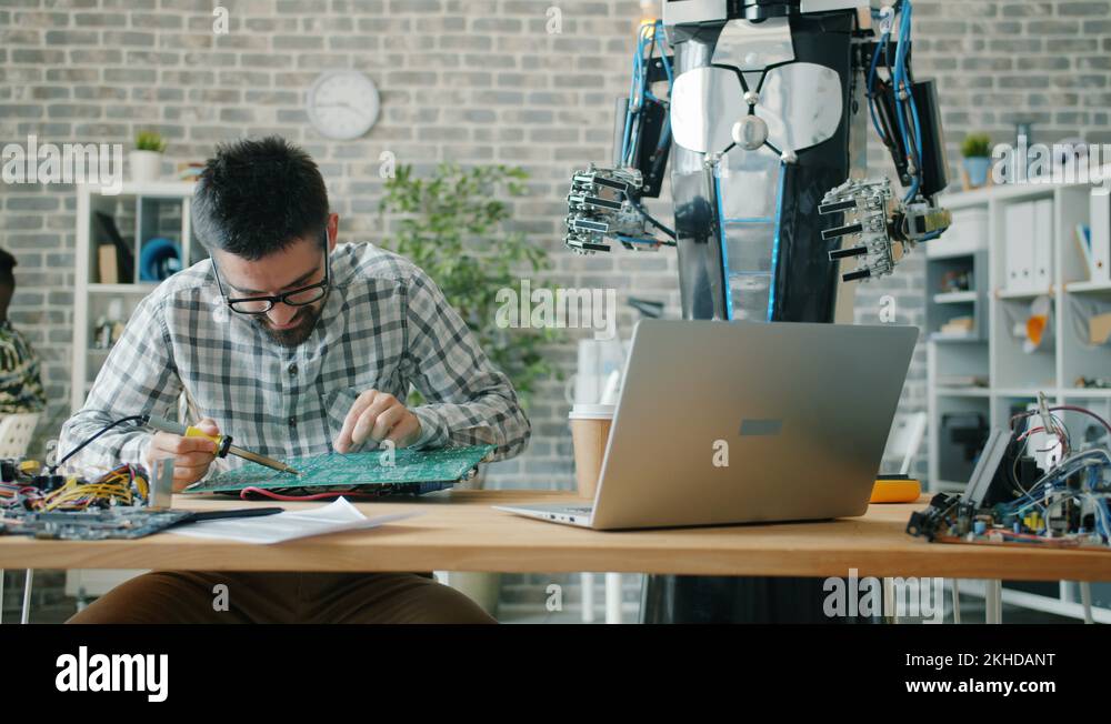 Robotics engineer guy using soldering iron to fix microcircuit in ...