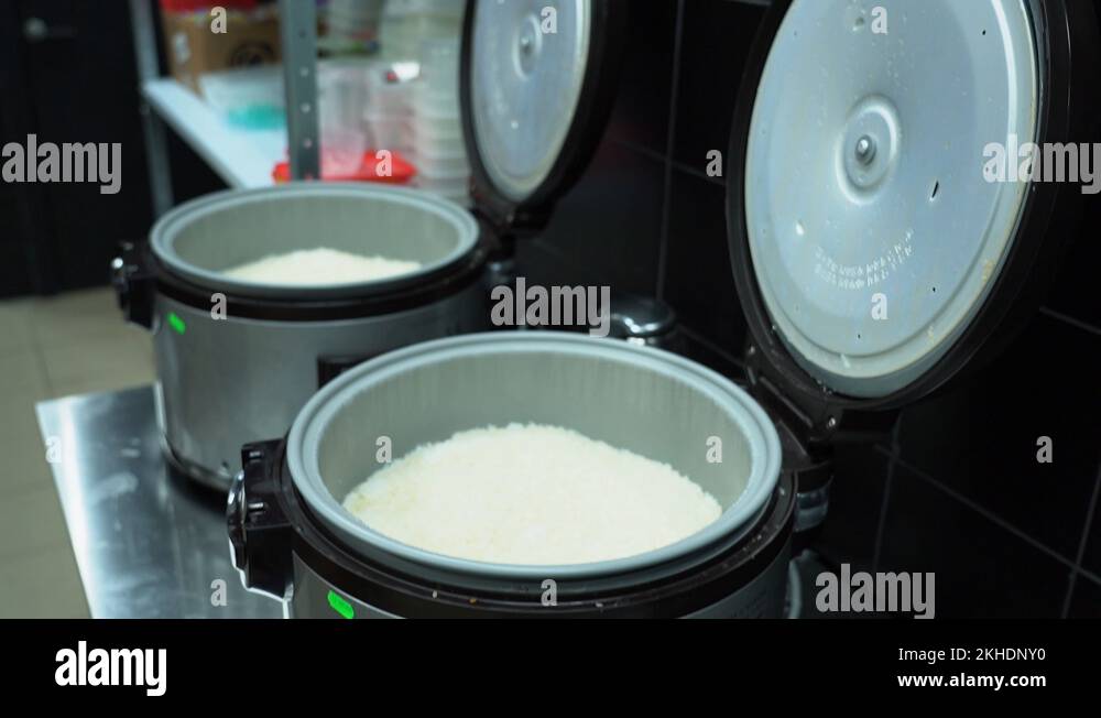 Two big open silver rice cooker cools on shine table on a black tile ...