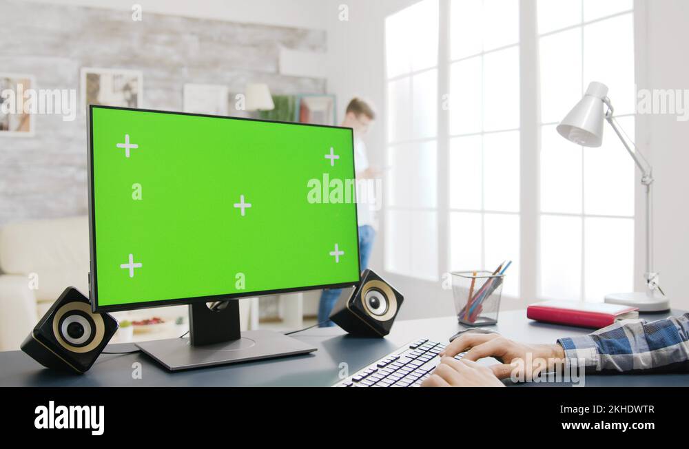 Zoom out footage of male typing on keyboard of a green screen PC ...