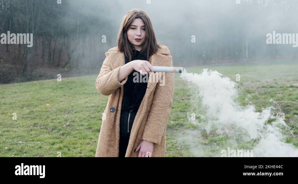 Woman makes emergency flare signal with white smoke. Hipster pretty ...