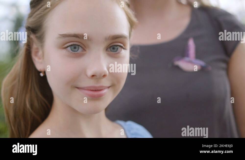 mother leans to her younger daughter, 10 years girl smiles , close-up ...