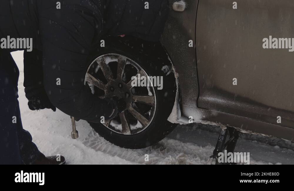 man raises car jack on road. man is changing wheel of car. replacement ...