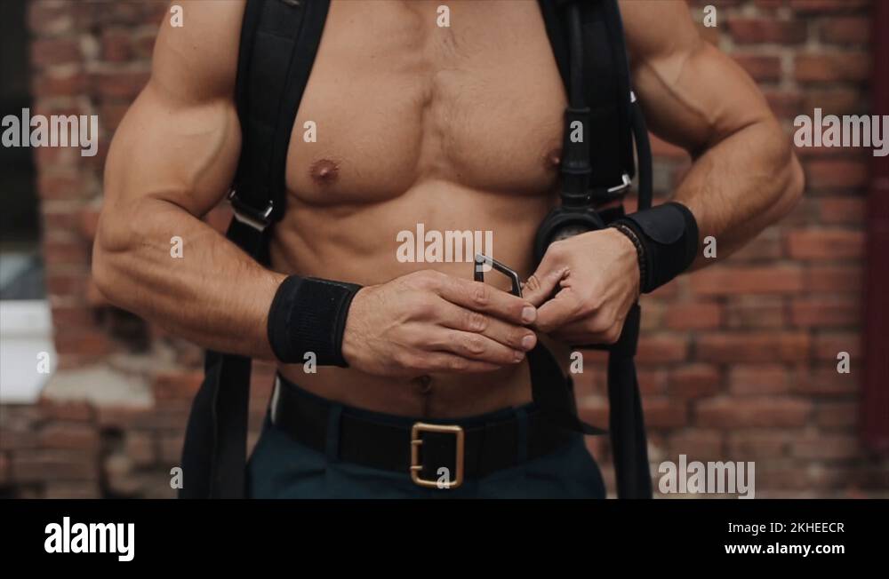 Close view of a handsome shirtless young man fastening belt of ...