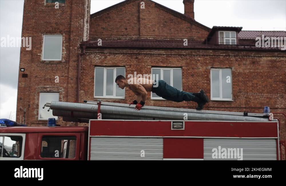Strong shirtless firefighter doing push-ups with crossed legs on top of ...