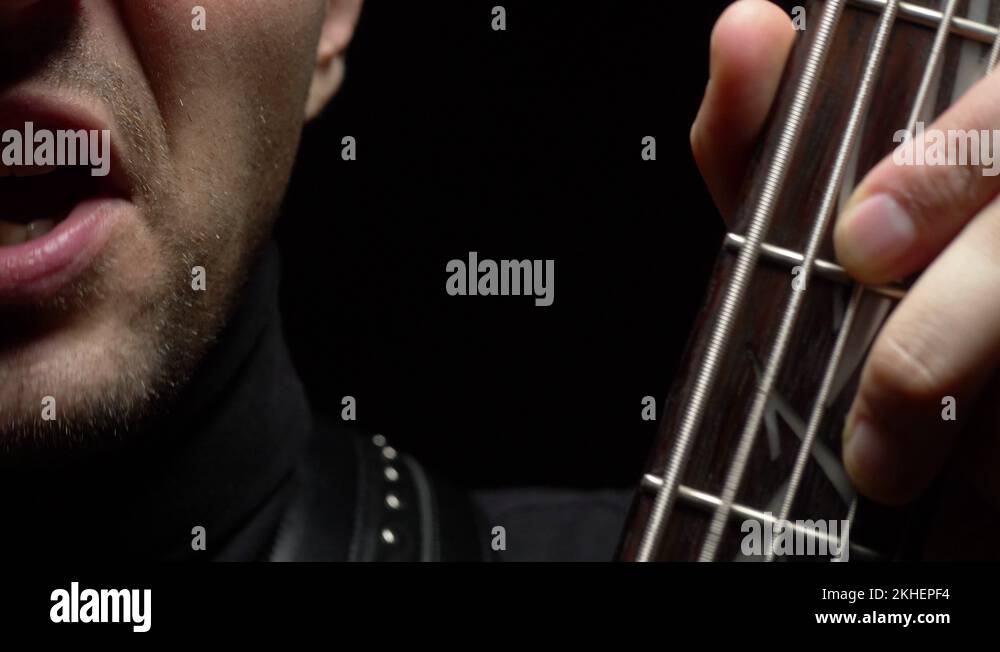 male face and fretboard of electric guitar closeup on black background ...