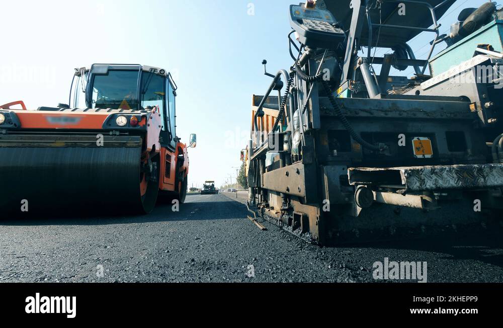 Fresh asphalt road with paving machines in a front view. Road ...