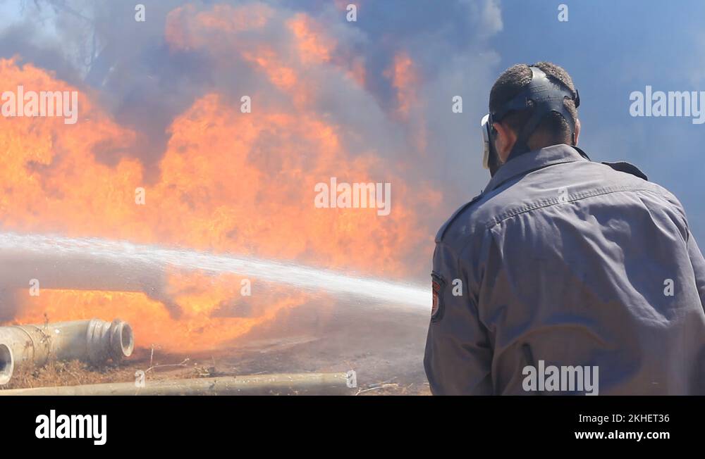 Fireman extinguishing burning grass forest Emergency flames smoke fire ...