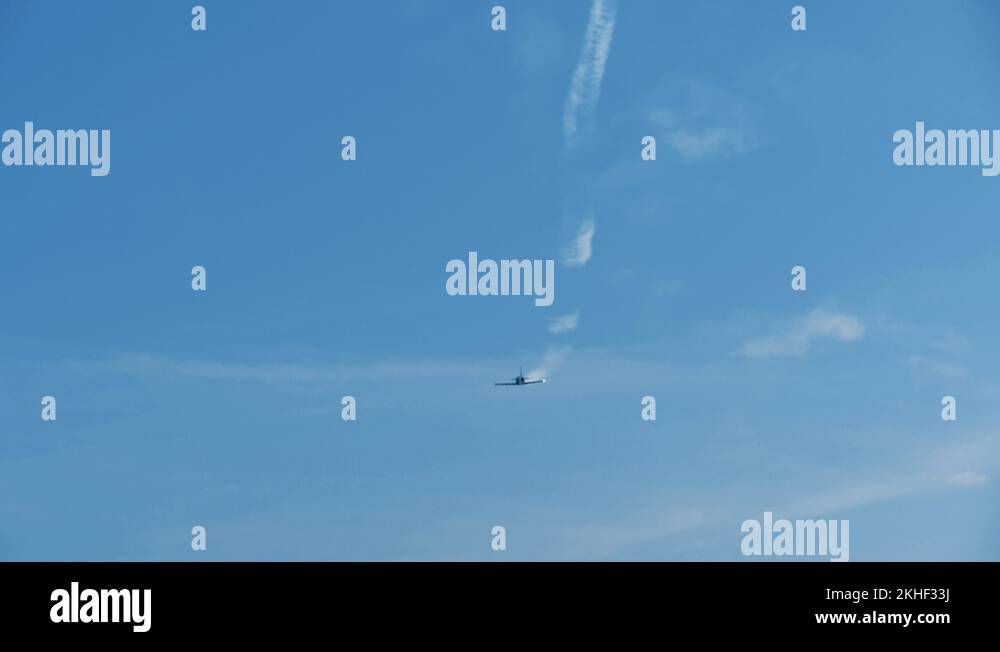 Black plane flies in sky, releasing smoke. Aircraft performs loops at ...