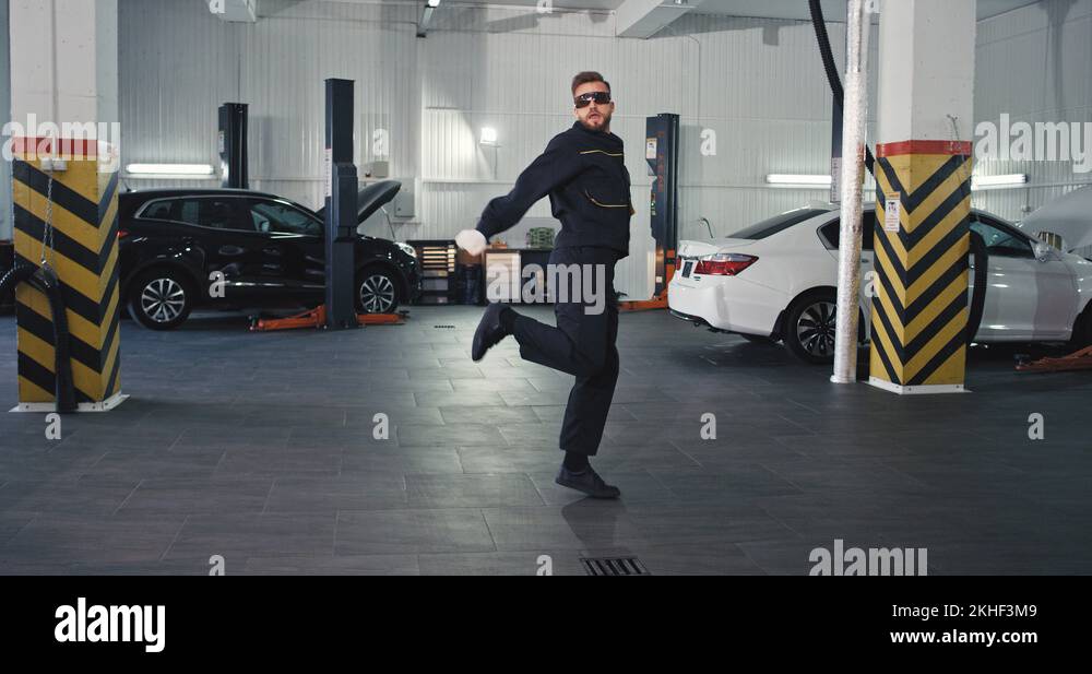 Mechanic guy with a uniform and black glasses dancing excited while ...