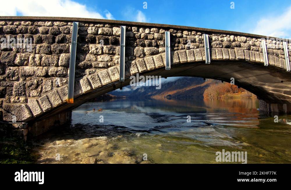 Slow motion right pan stone ancient arch bridge rapid river leaving ...