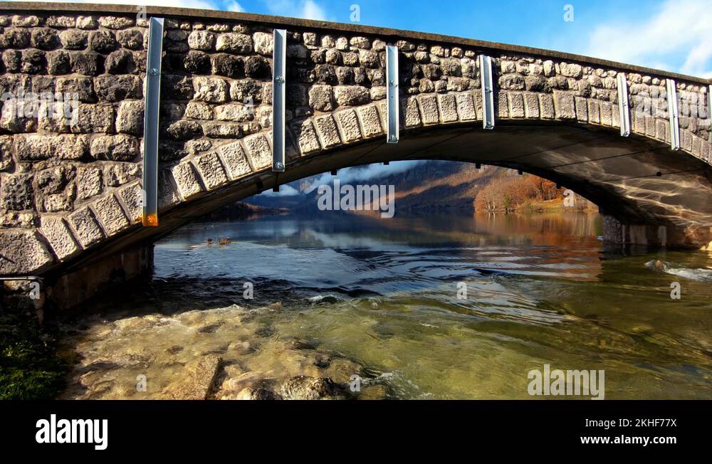 Slow motion tilt up stone arch bridge flooded rapid river leaving ...