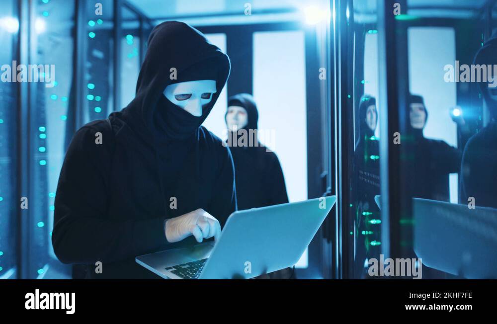 Hooded computer hacker typing programming code on laptop copying ... Hooded computer hacker typing programming code on laptop copying ...