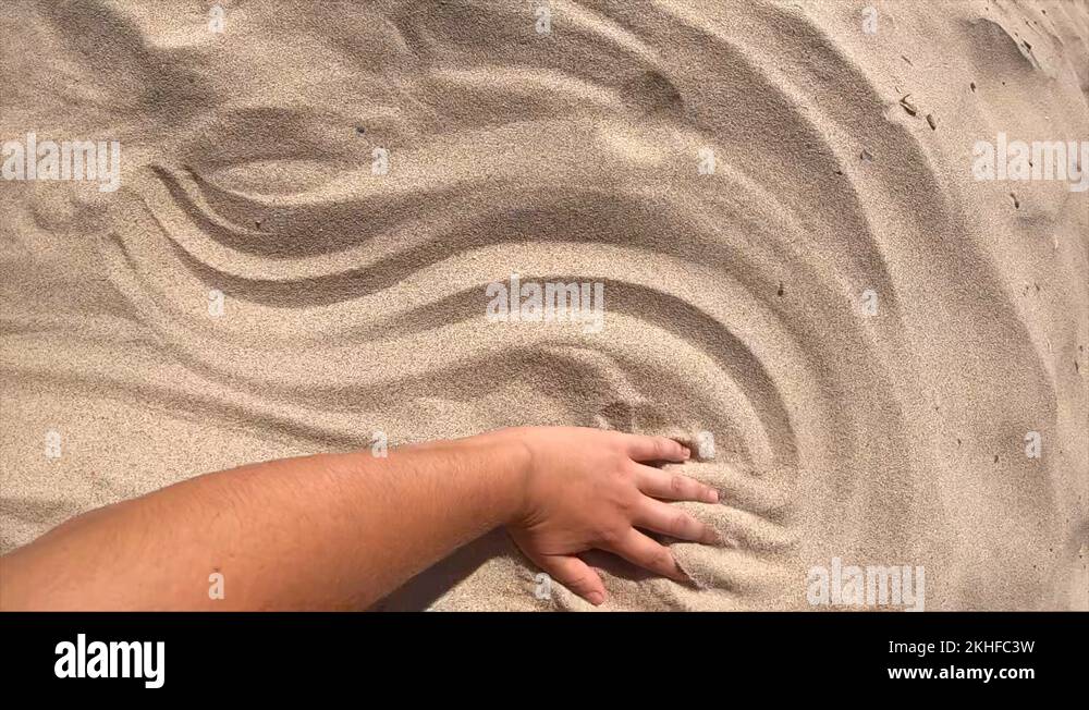 Hand movement on the sand surface, top view. Man's hand scatters Stock ...