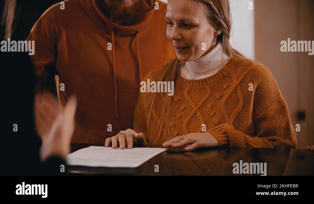 A family checking in the luxury hotel - a smiling woman signing the ...