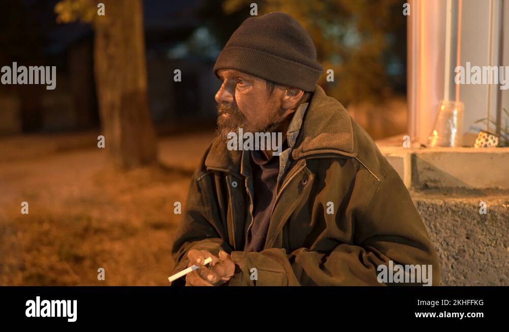 Homeless sick man smoking cigarette on the street at night Stock Video ...
