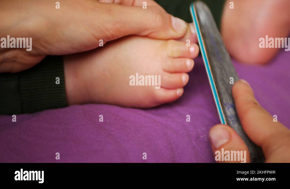 Nail cutting on the feet of the child. Mother woman cuts the toenails ...