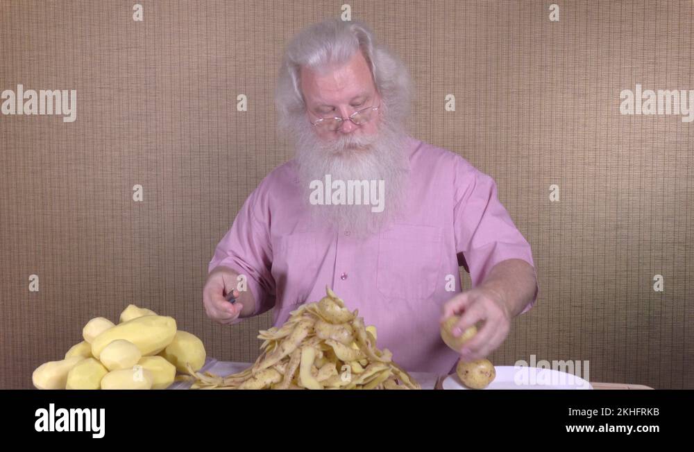 Senior thickset Caucasian man with grey hair and beard is peeling ...
