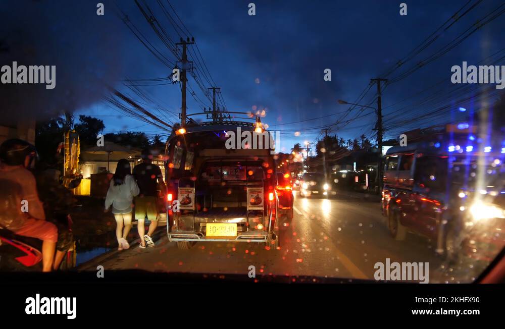 Thai songthaew bus with lit headlights traveling along night street ...