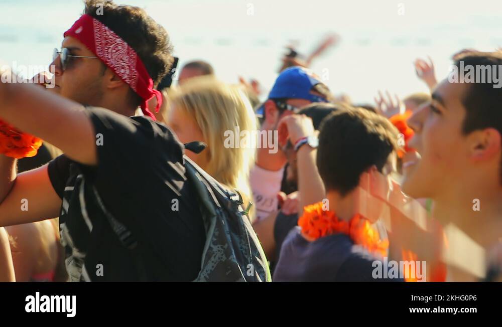Crowd of young people dancing at the beach party. People dancing on the ...