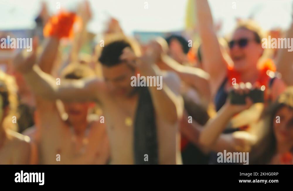 Crowd of young people dancing at the beach party. People dancing on the ...