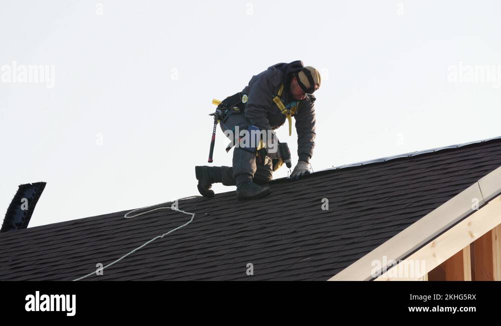 Tiler makes roof ridge using hydraulic hammer. Frame house under ...