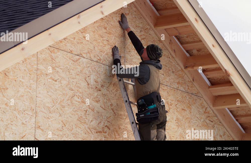 Builder covers frame with plywood using hammer. Frame house under ...