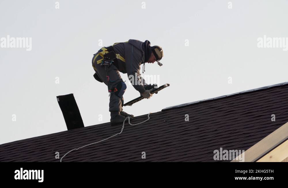 Tiler makes roof ridge working on the rooftop. Frame house under ...