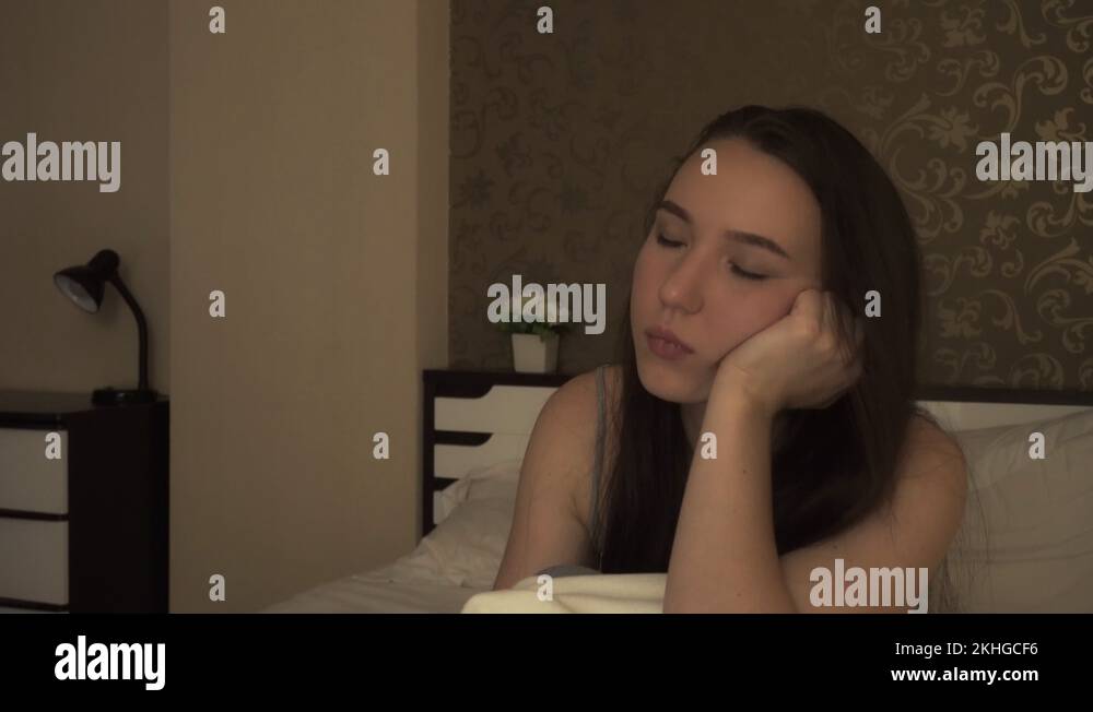 A young girl sits on a bed in a sleeping state Stock Video Footage - Alamy