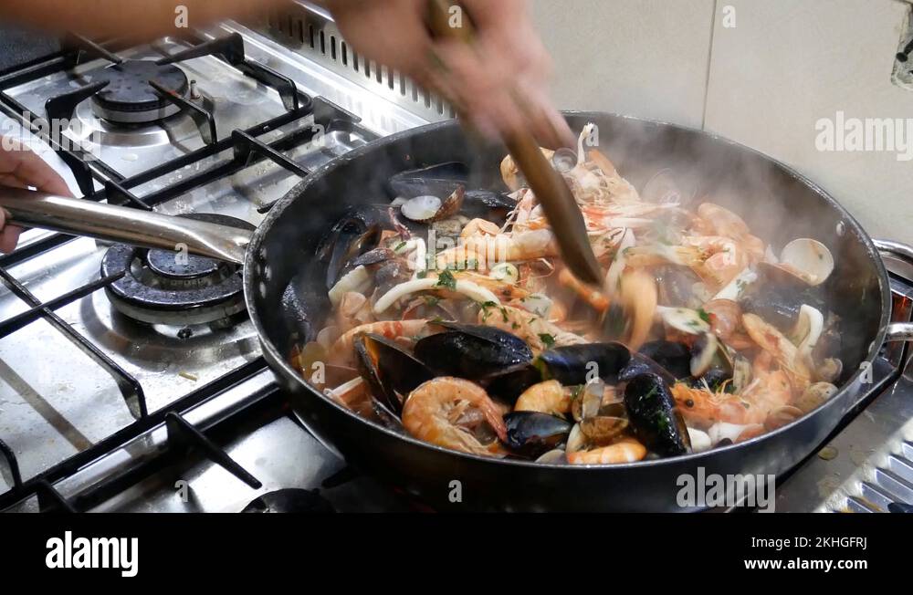 Cooking and mixing seafood in the pan. The chef cooks a delicious fish ...