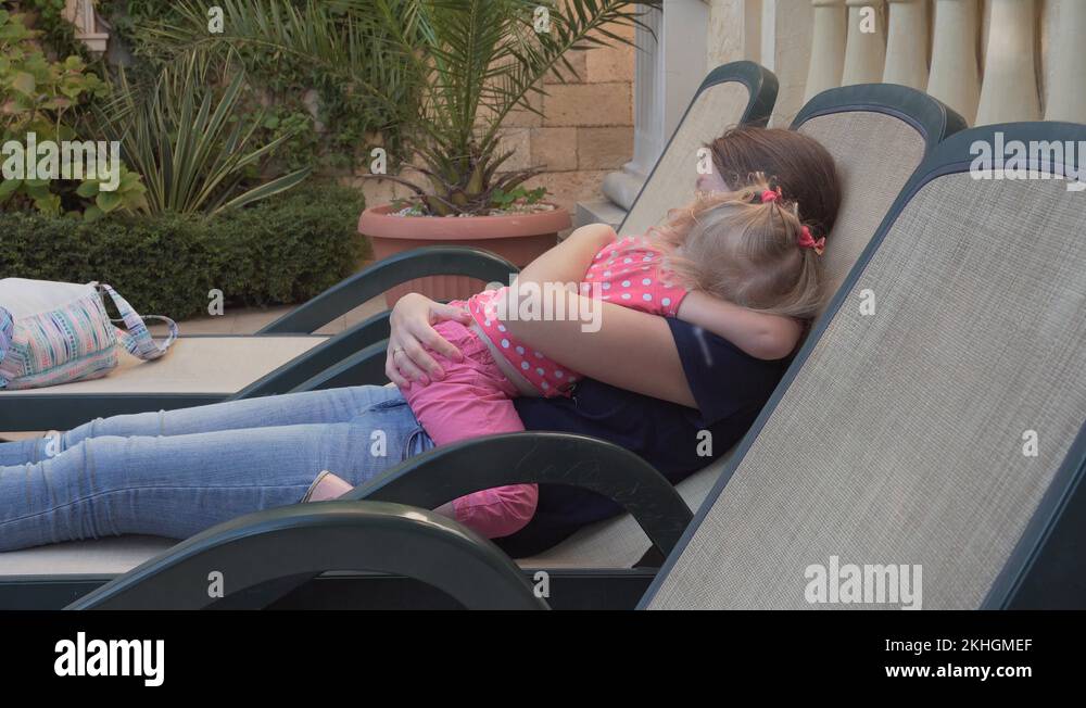 Close-up. Daughter falls asleep in mom arms in a deck chair Stock Video ...