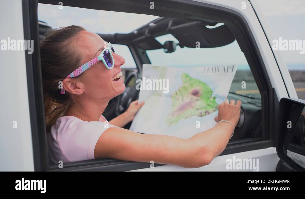 Woman driver sitting inside her vehicle looking at road map for ...