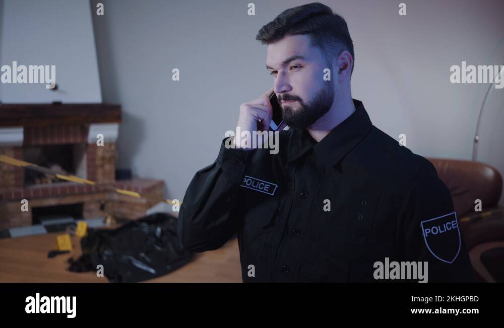 Bearded Caucasian young police officer standing at the crime scene and ...