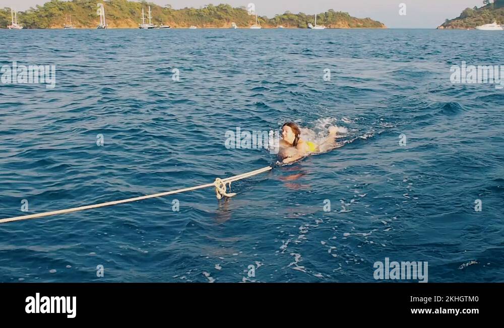 pulled out of the water on Board a boat, a young woman swims behind a ...