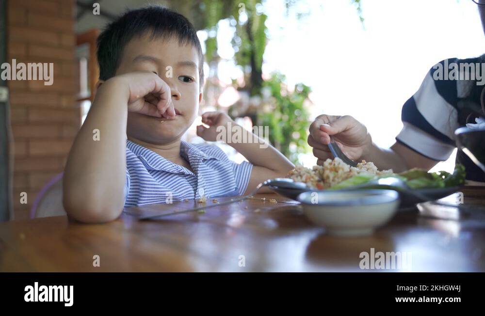 Asian boy eating and sharing stir fried rice food with his mother Stock ...