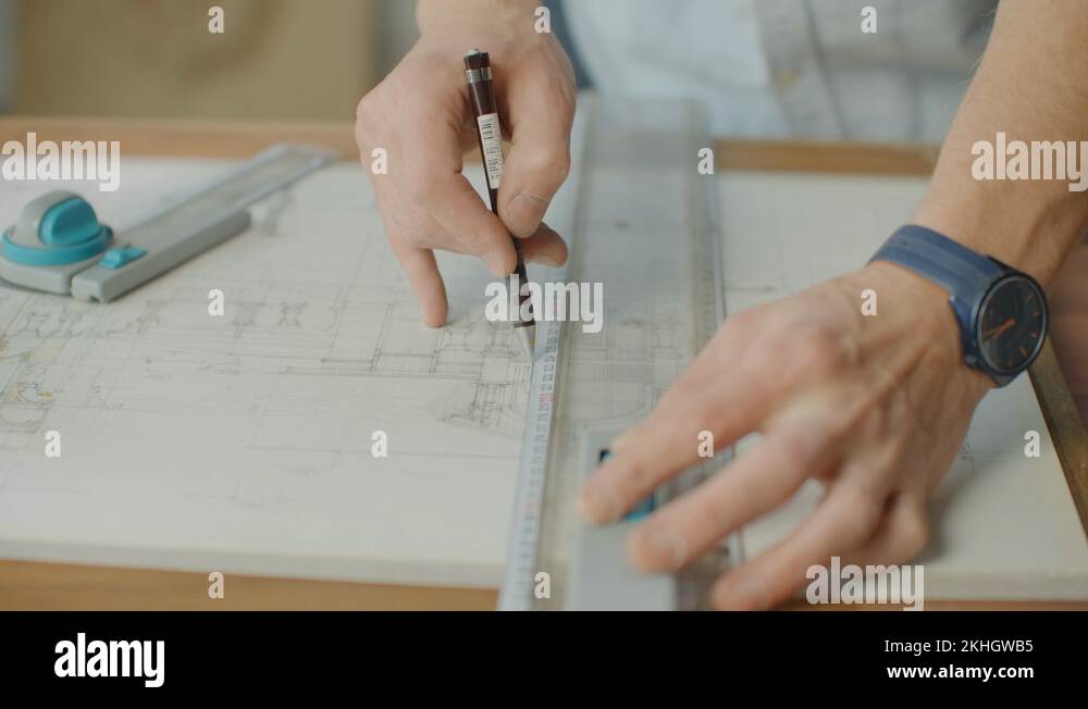 Engineer draws buildings on the table using a pencil and ruler. An ...