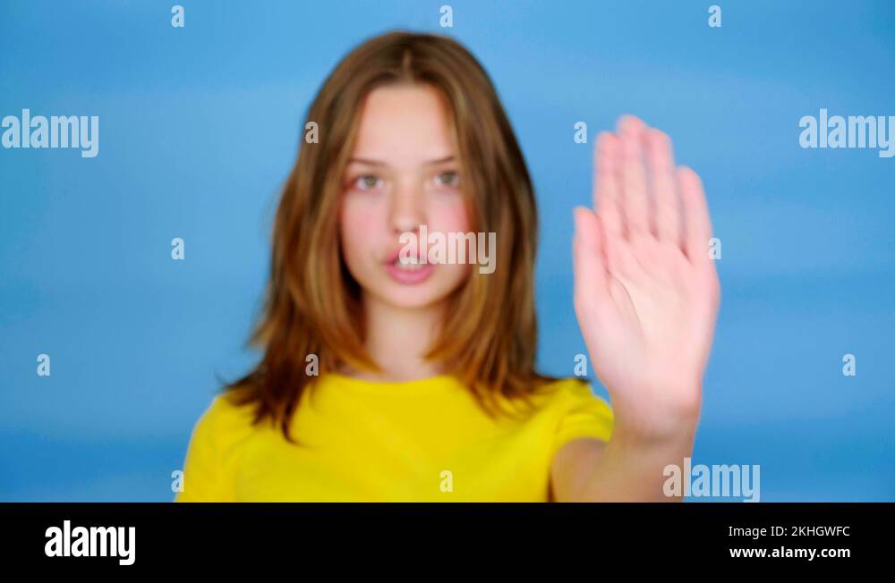Teen girl is looks at camera, holds out her hand in a front and says ...