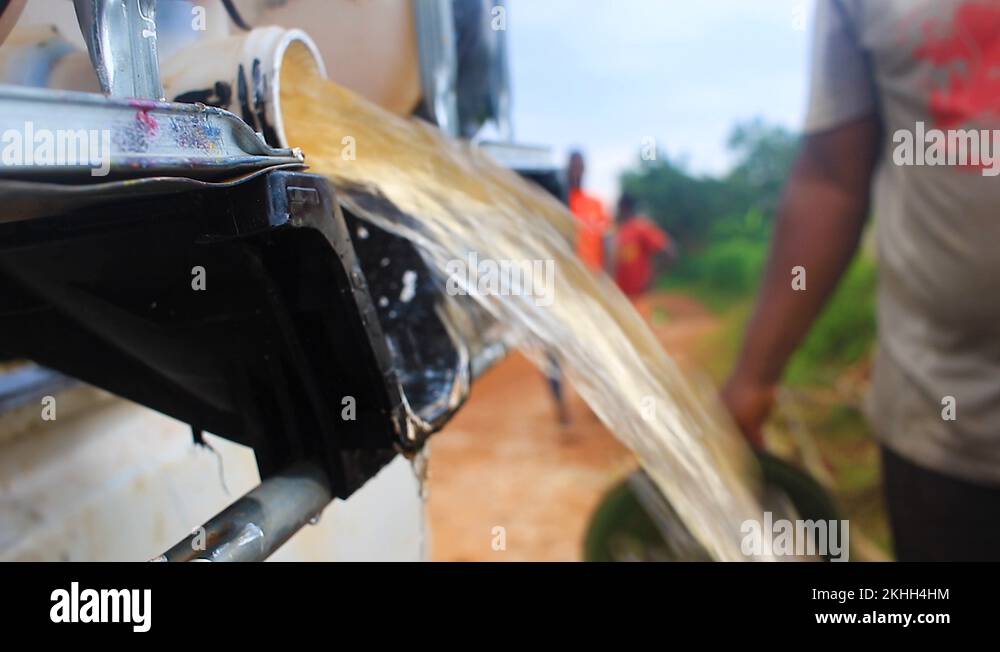 A close up shot of water flowing out of a tank and an African in the ...