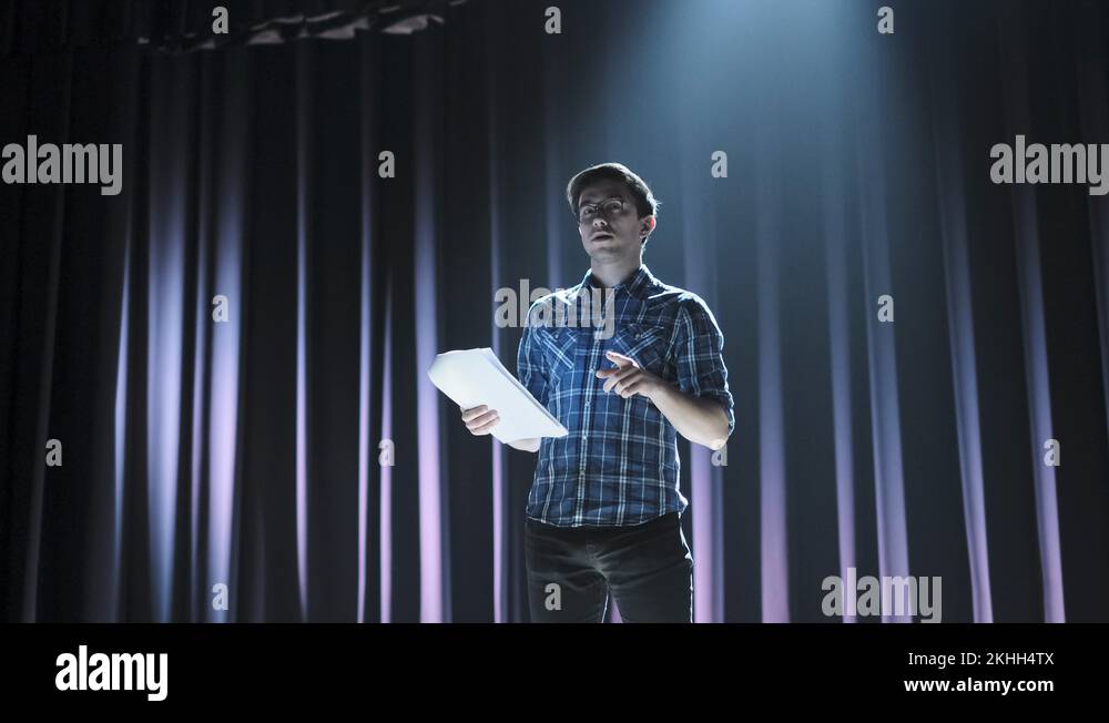 Stand up comedian on stage. Young man talks joke into microphone or ...