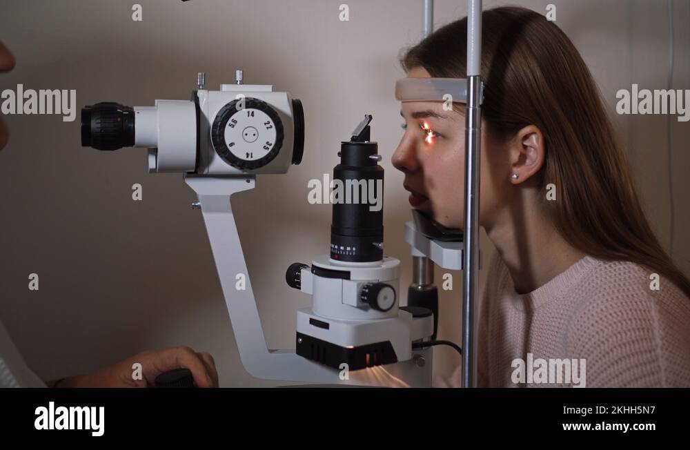 Young pretty girl is checking eyesight with optic ophthalmic device ...