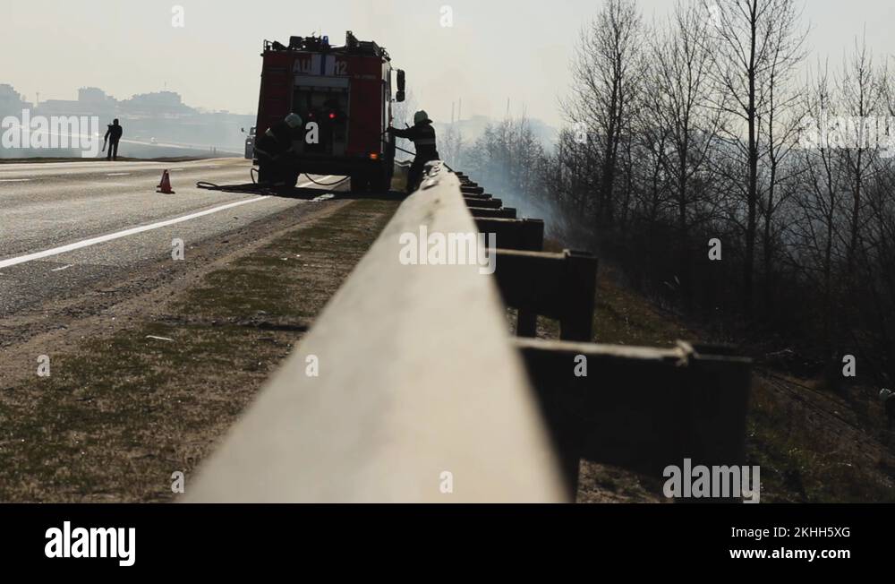 Firefighters uncoil a fire hose from a fire truck across the road to ...