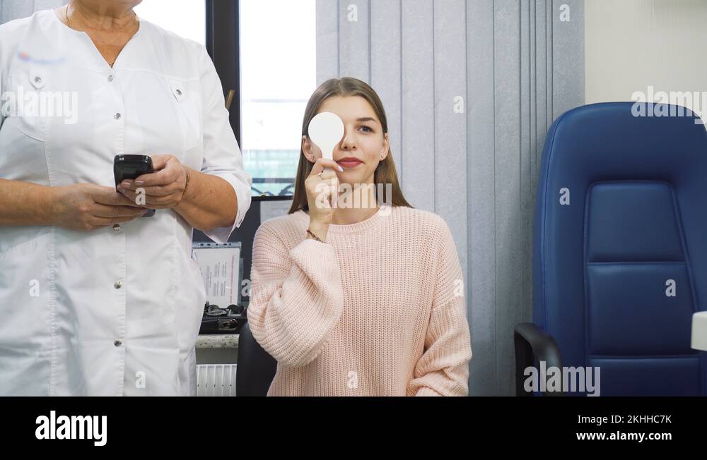 Pretty young girl model is checking her eyesight by closing one eye ...