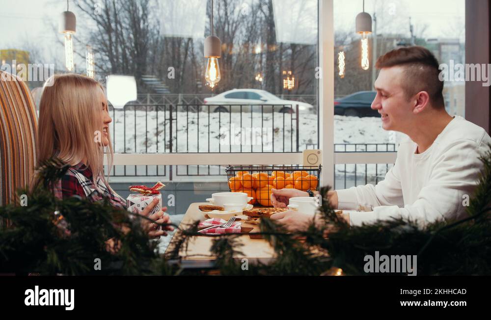 A cute couple having lunch - a woman gives her boyfriend a gift - he ...