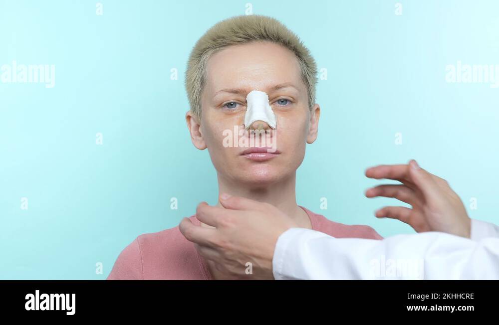 the doctor hands touches the face of a woman with a bandage on her nose ...