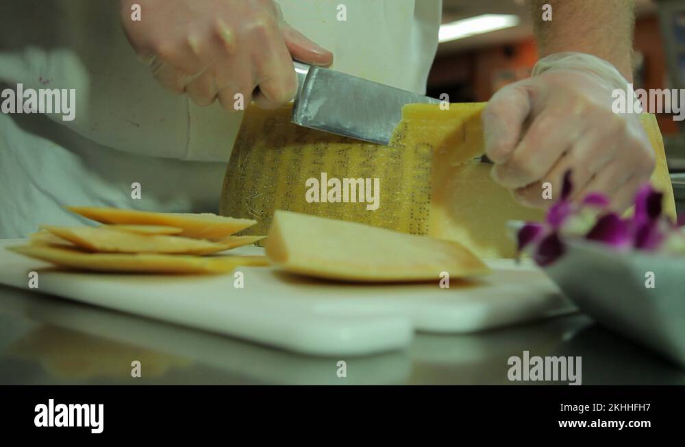 Chef. Cuts wheel of parmesan cheese in commercial kitchen. cu A Stock ...