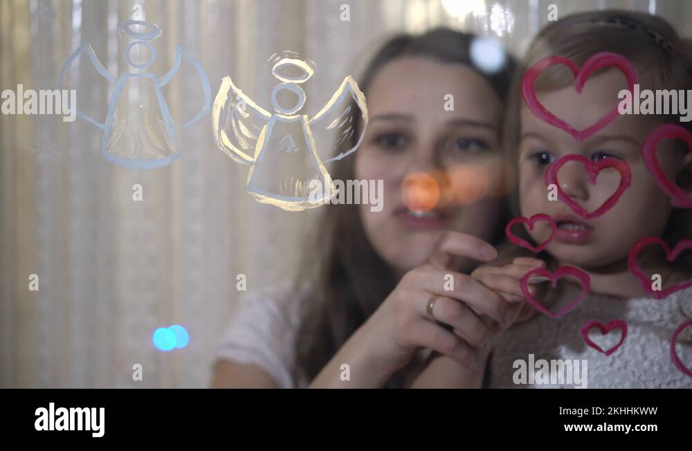 Mom with little daughter draw heart and angel paints on glass Stock ...