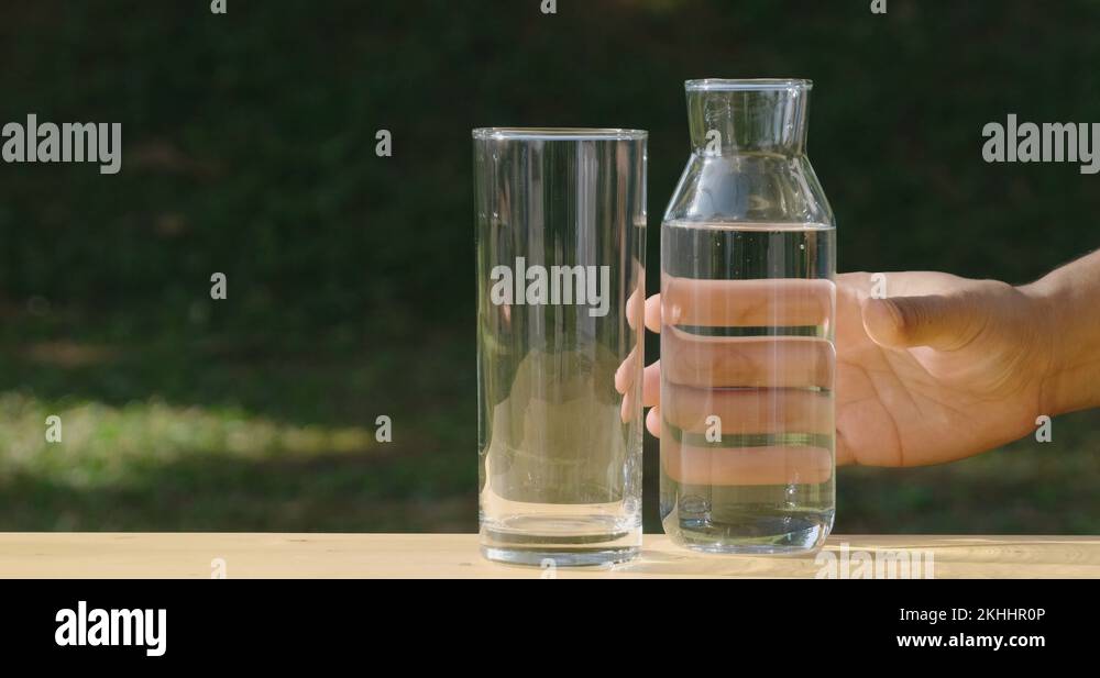 Human hand pick up the bottle and pouring pure water in to the glass ...