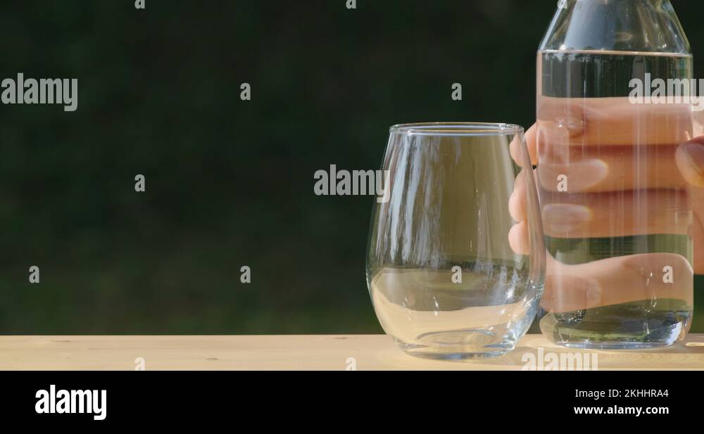 Human hand pick up the bottle and pouring pure water in to the glass ...