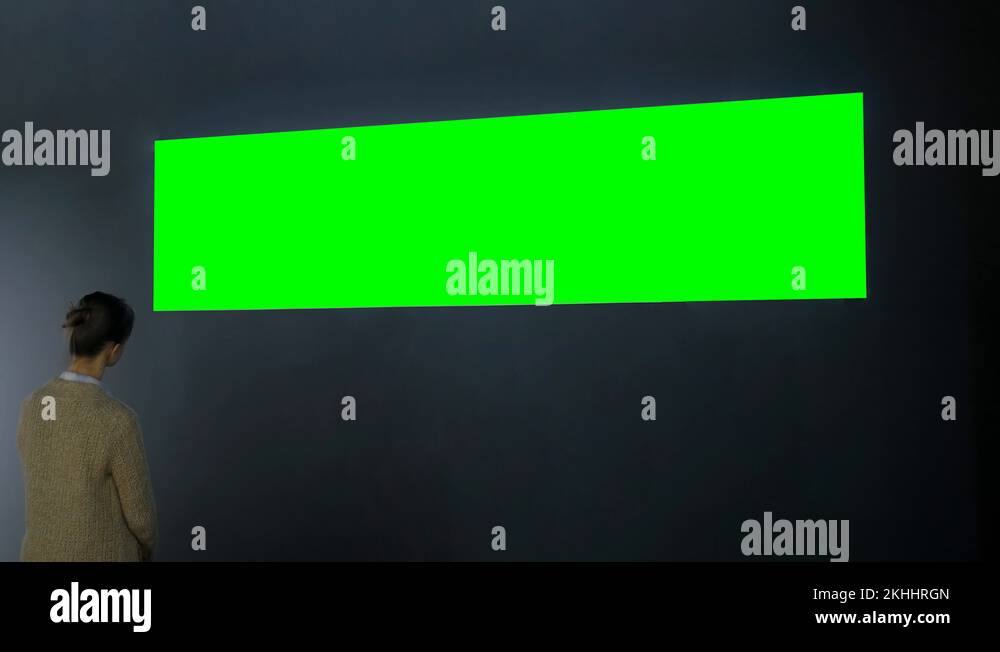 Woman looking at large blank green screen - chroma key concept Stock ...