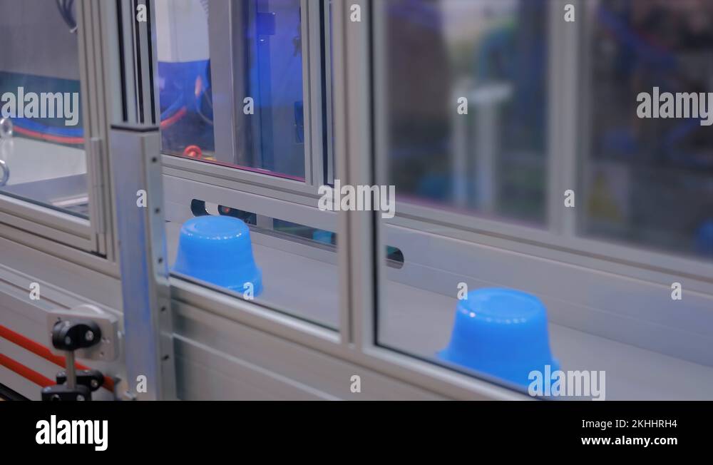 Blue pots on conveyor belt of plastic injection molding machine with ...